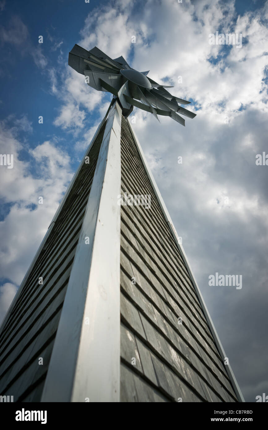 Unusual perspective of a tall, wooden windmill under a cloudy blue sky ...
