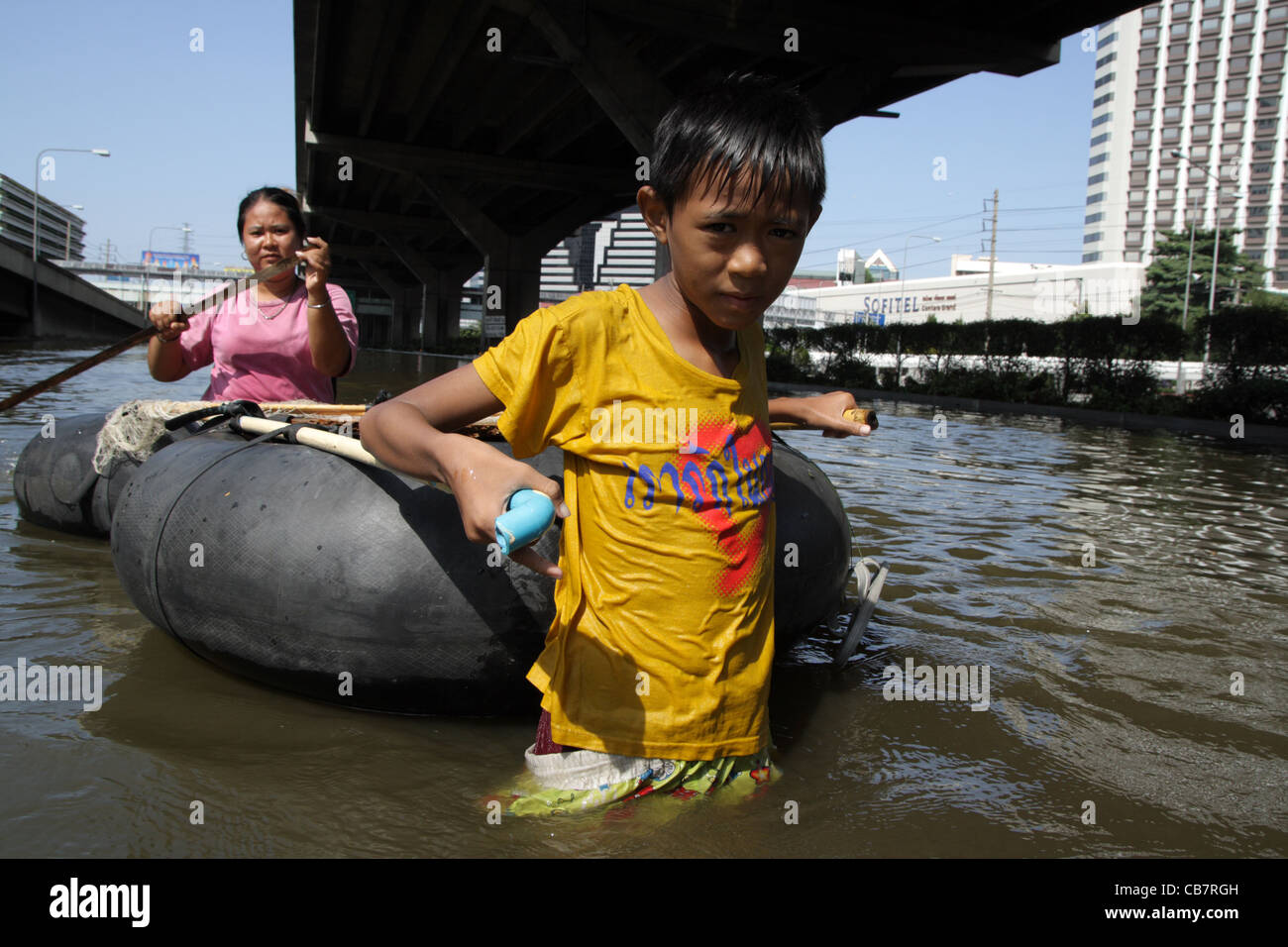 A boy pulling rubber ring boat in floodwaters at Vibhavadi road ...