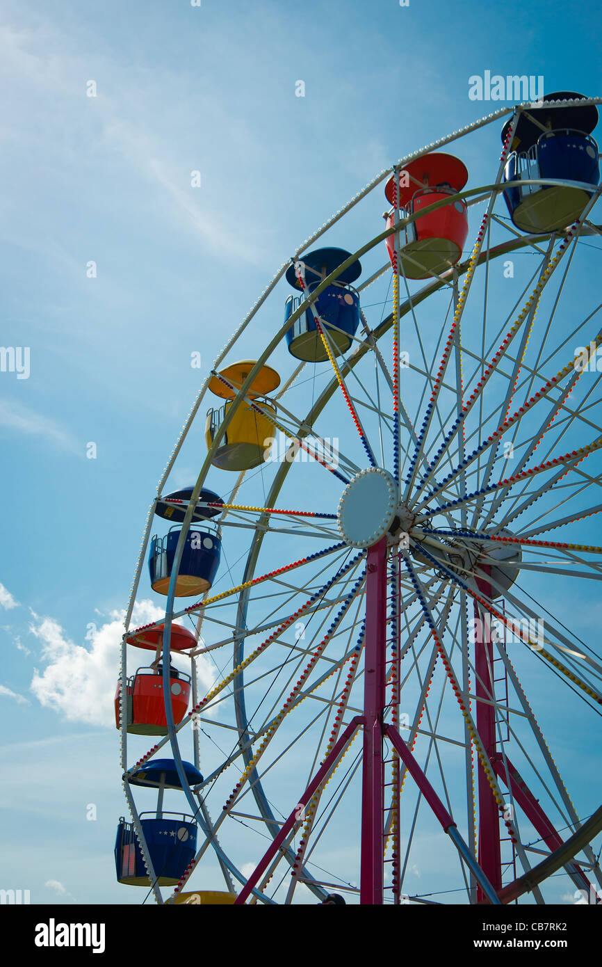 Looking up at a large, multi-colored ferris wheel set against a bright ...