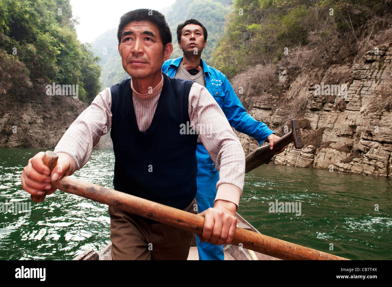 China, Yangtze River. Two boatmen steer a traditional peapod boat along ...