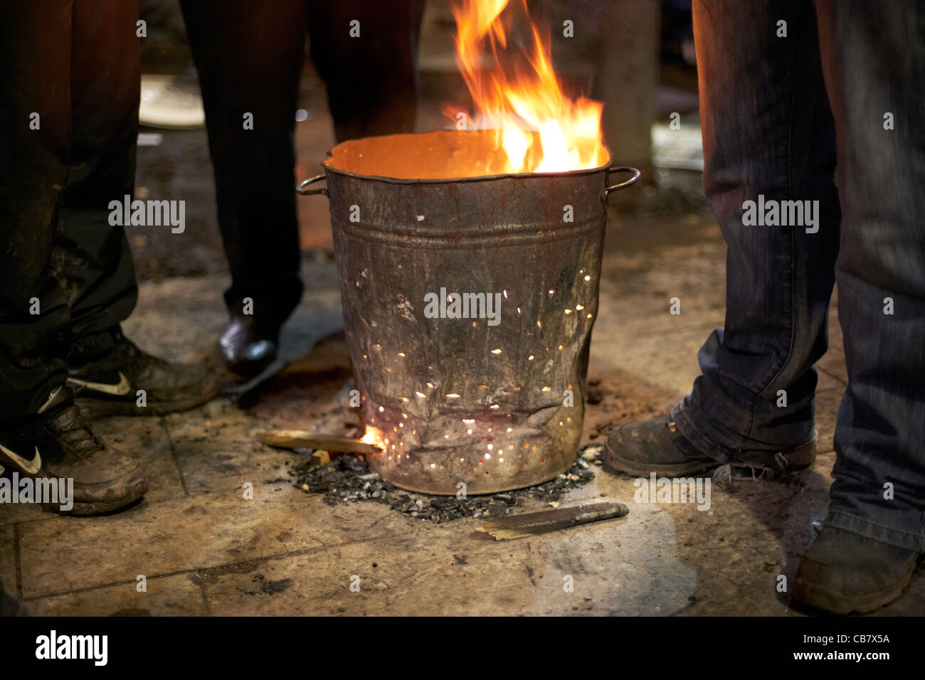 men standing around brazier burning wood and coal on a cold night in ...