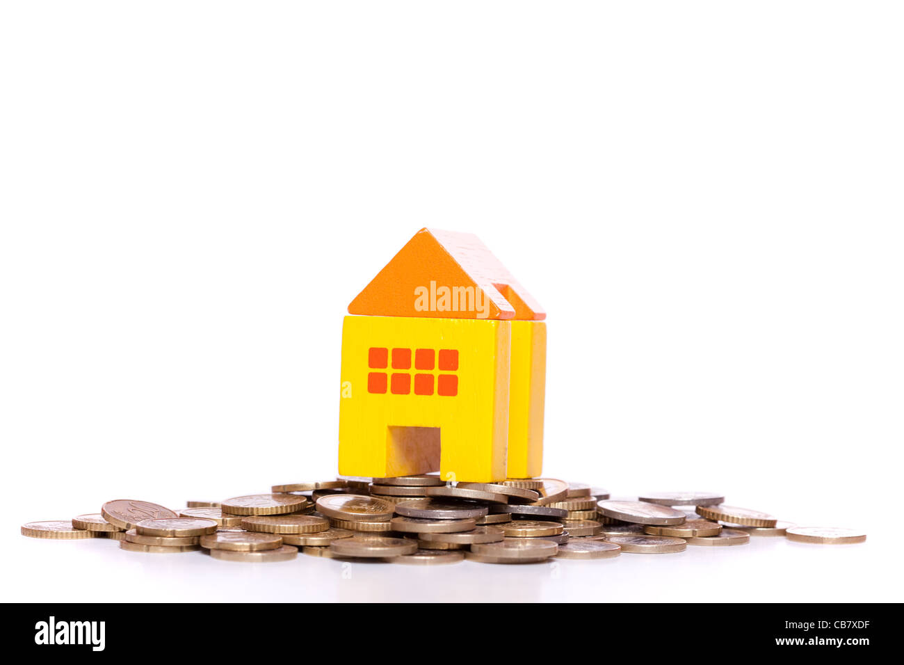 yellow toy house over a lot of golden coins (isolated on white Stock ...