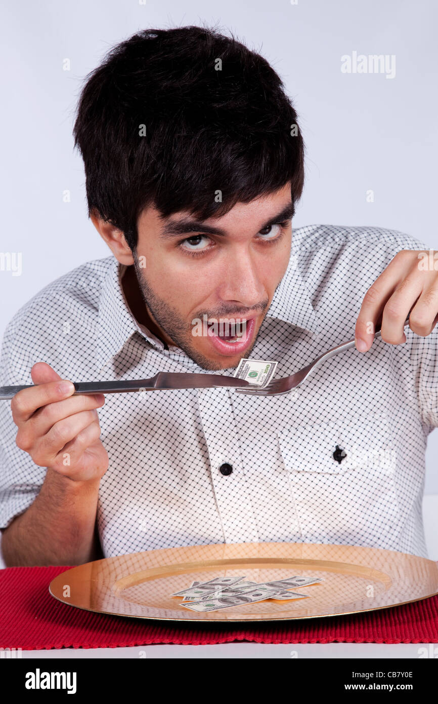 Man eating money at a plate with a fork and a knife Stock Photo - Alamy
