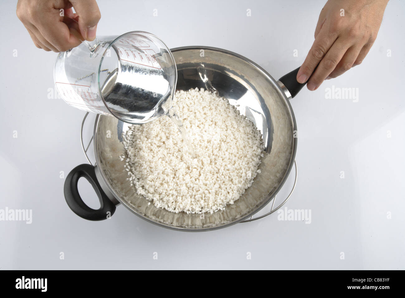 Pouring water over the rice to boil Stock Photo - Alamy