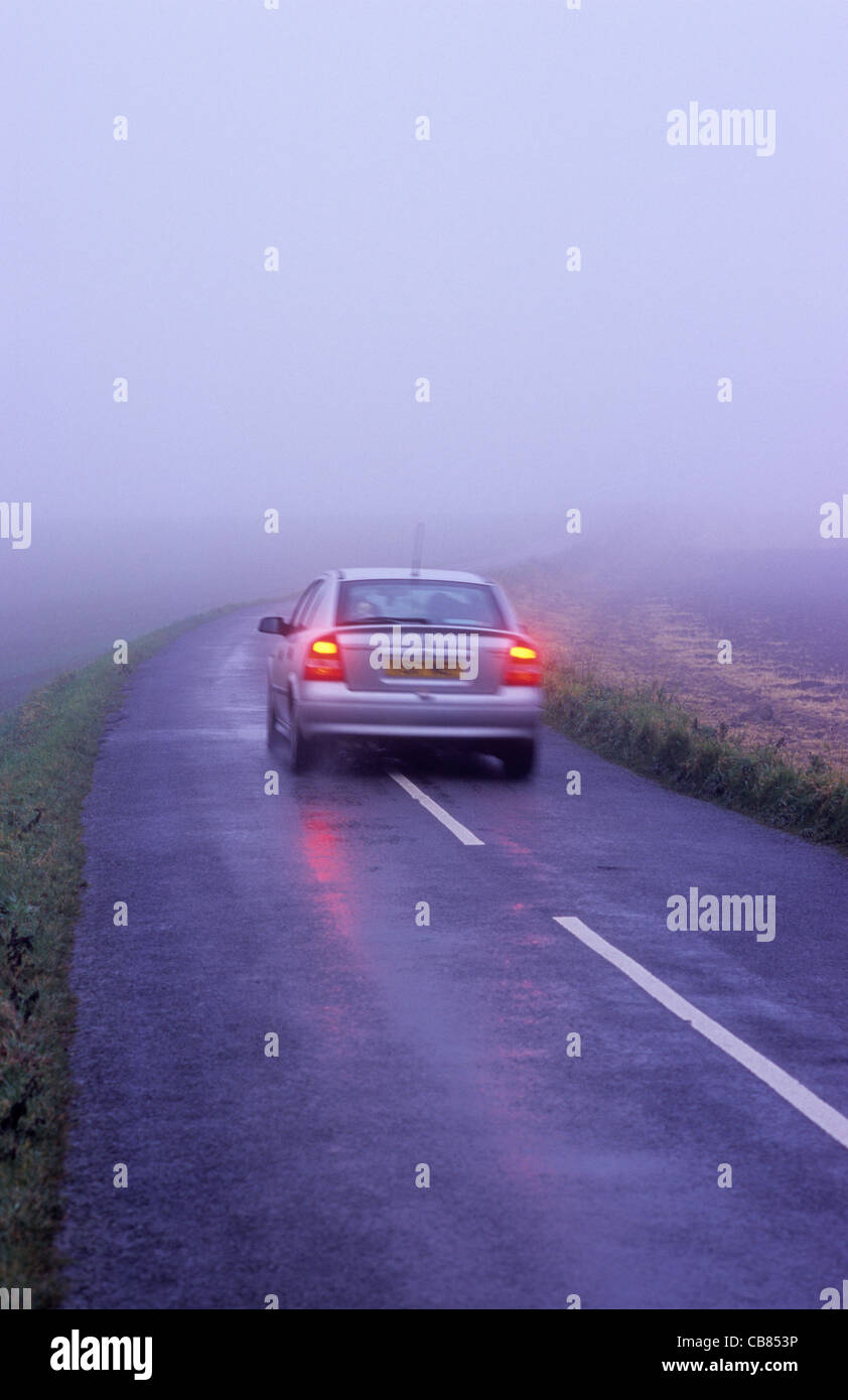 fog lights on car travelling through thick fog on country road uk Stock ...