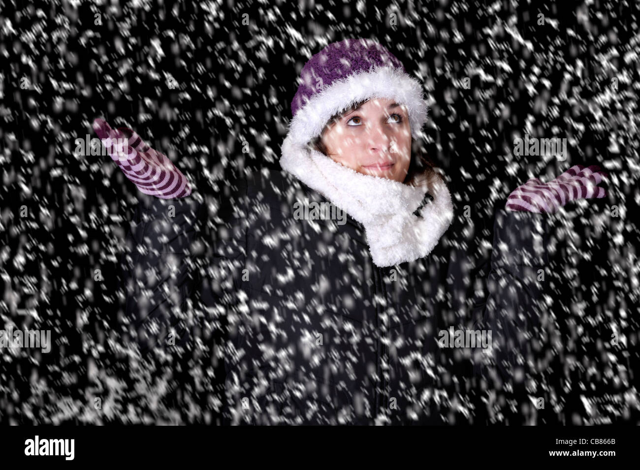 snowstorm: snowing on young woman in winterclothes looking up Stock ...