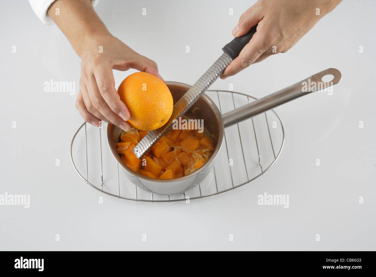 Grating orange over pumpkin Stock Photo - Alamy