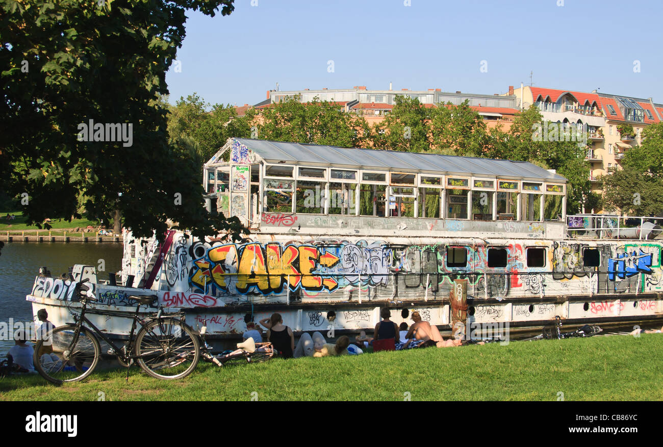 Graffiti painted wrecked ship at Spree River bank. Kreuzberg district ...