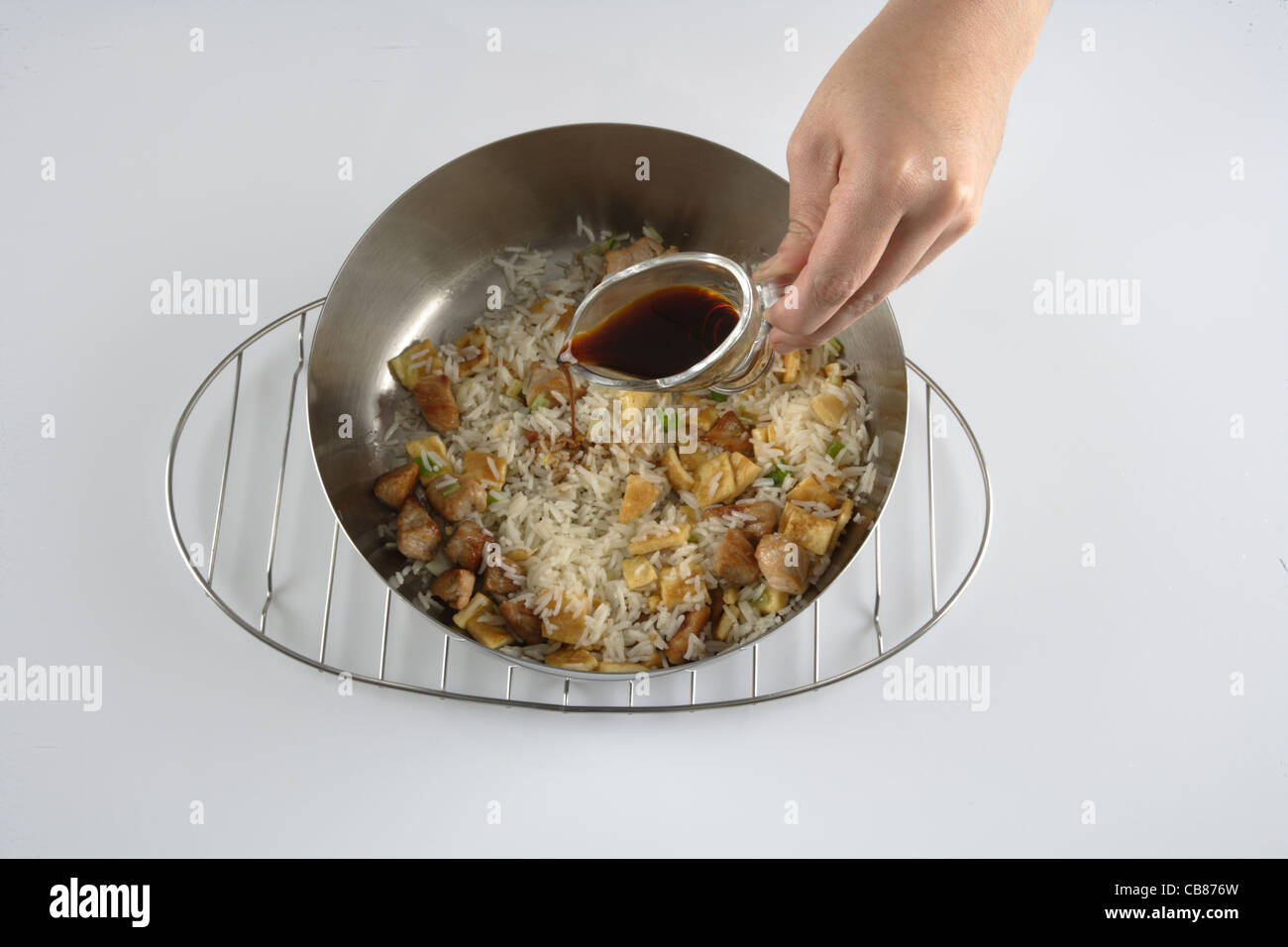 Adding soy sauce to rice with meat Stock Photo - Alamy