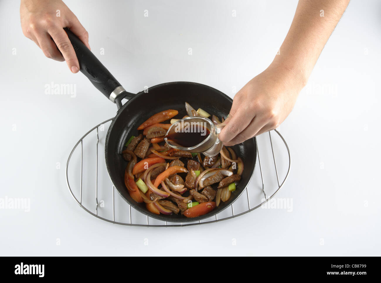 Adding soy sauce to meat with vegetables Stock Photo - Alamy