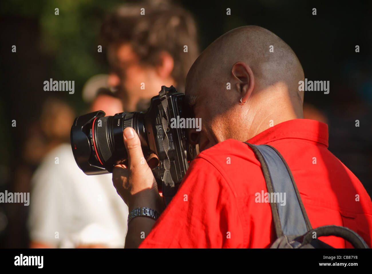 A man in red shirt shooting photo with professional dslr camera. Berlin ...