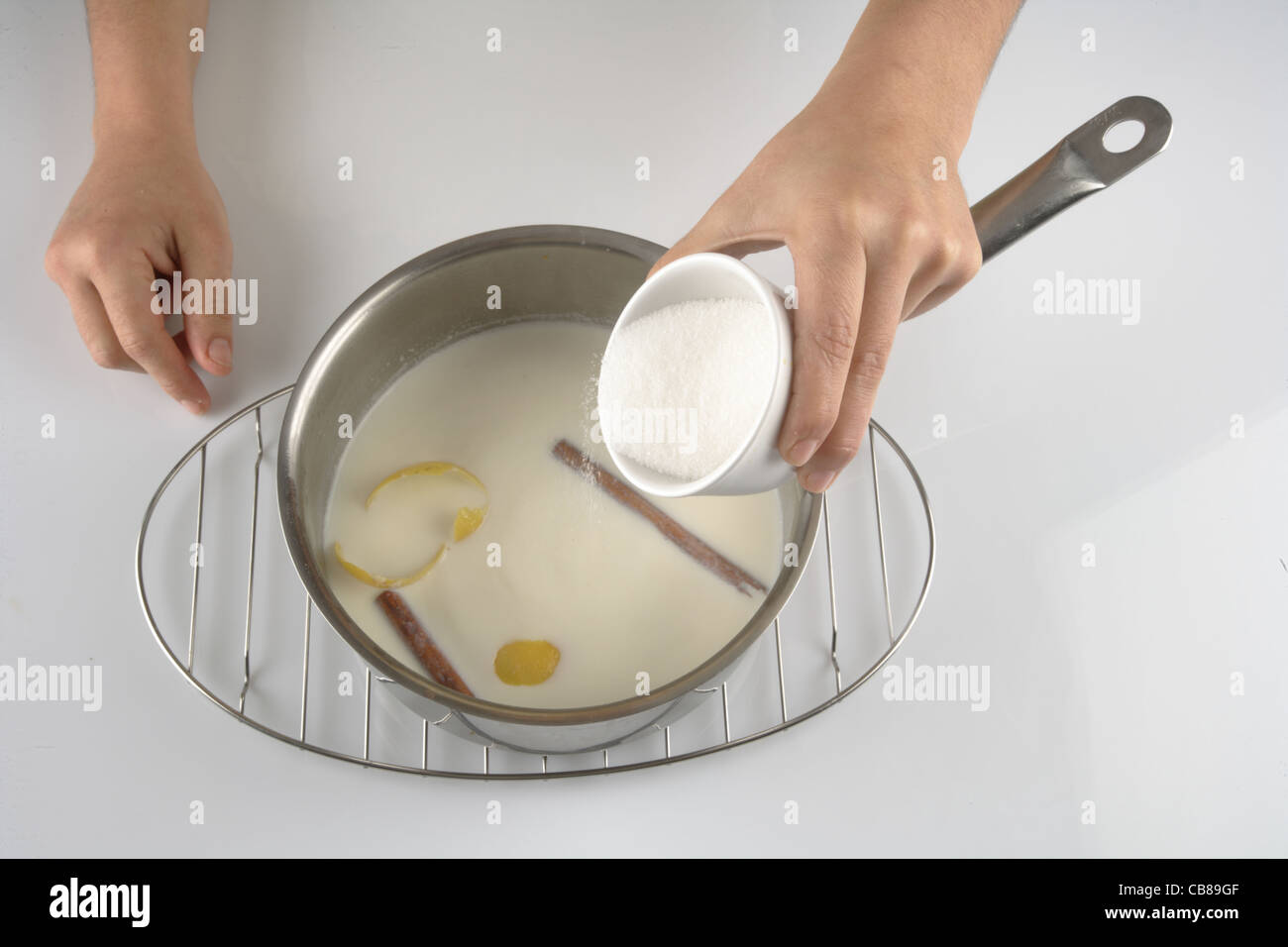 Adding sugar to the milk with cinnamon and lemon Stock Photo - Alamy