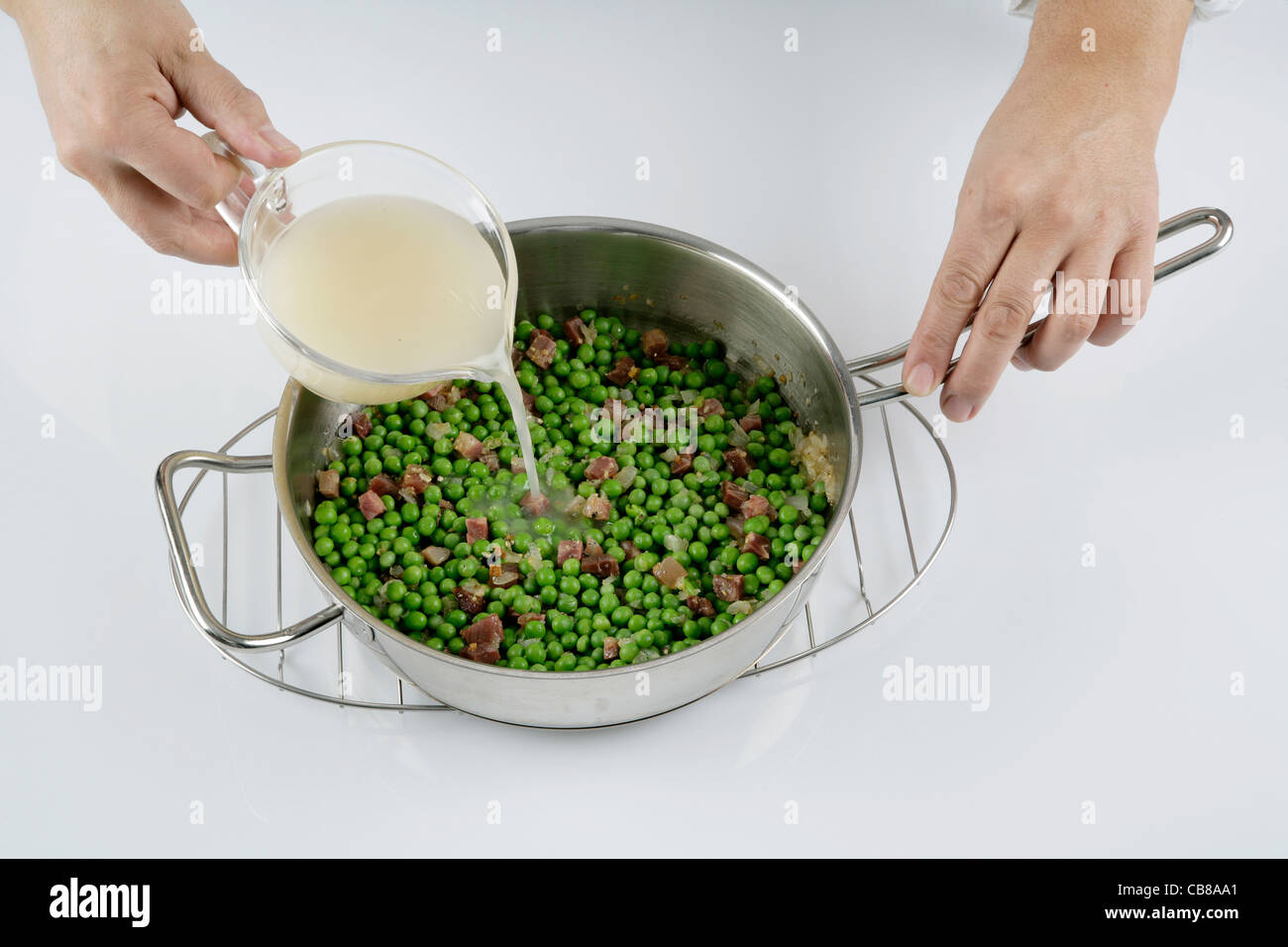 Pouring vegetable stock over peas with ham Stock Photo - Alamy