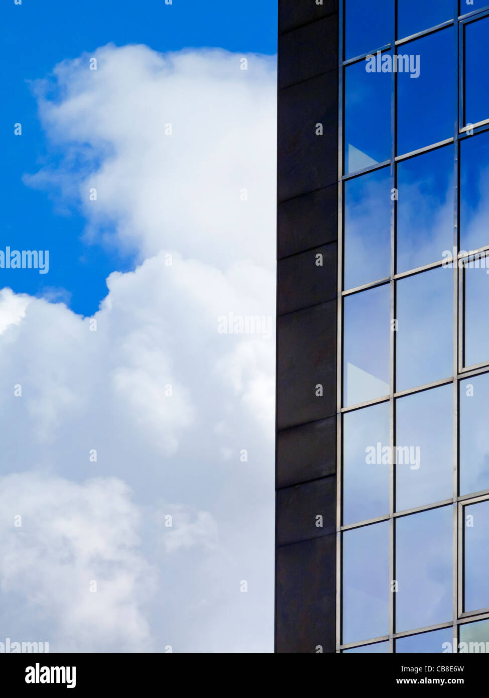 Modern glass office block window with cloud and sky reflected in the ...