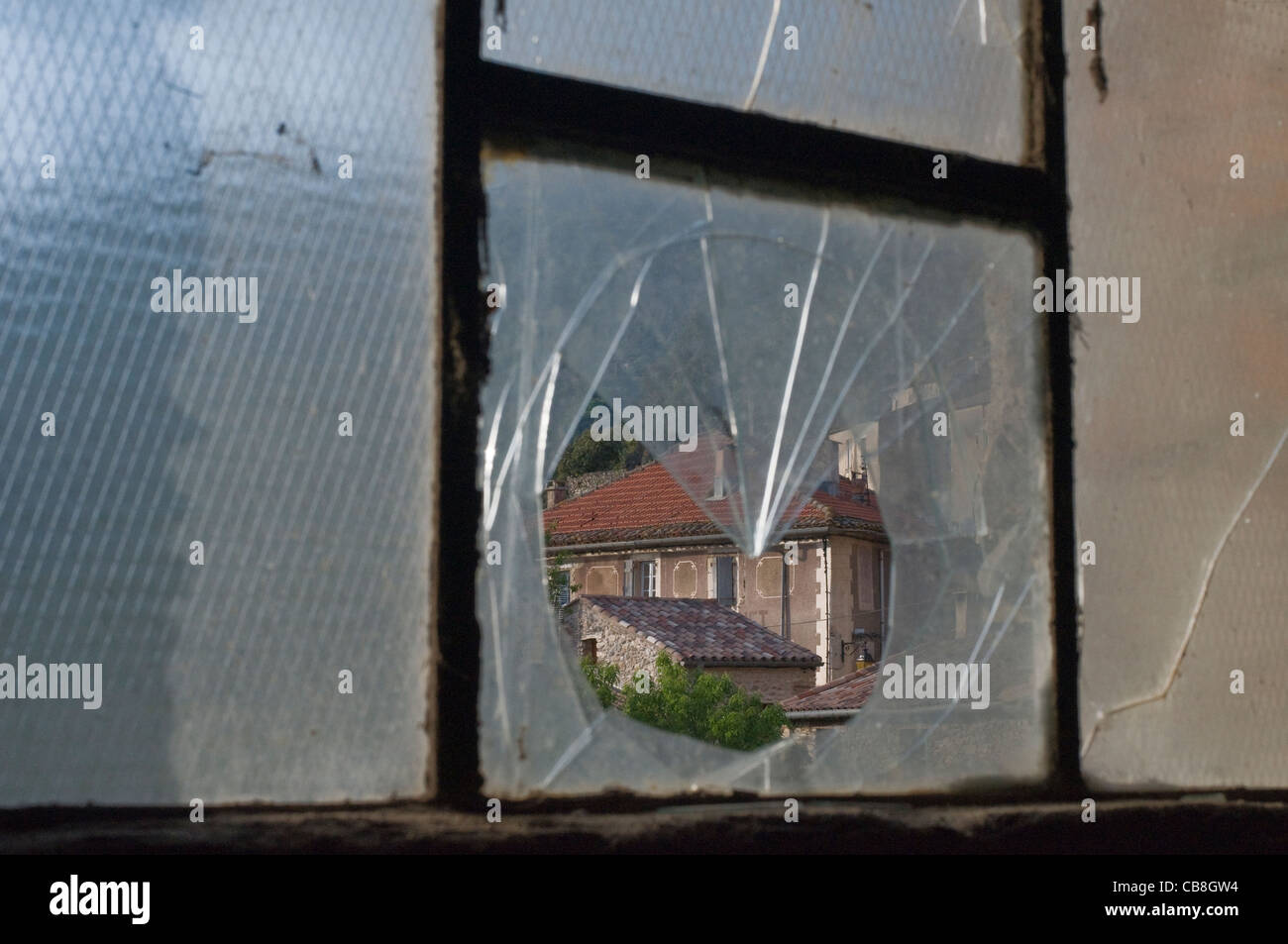 Broken window pane in derelict property showing house in distance Stock ...
