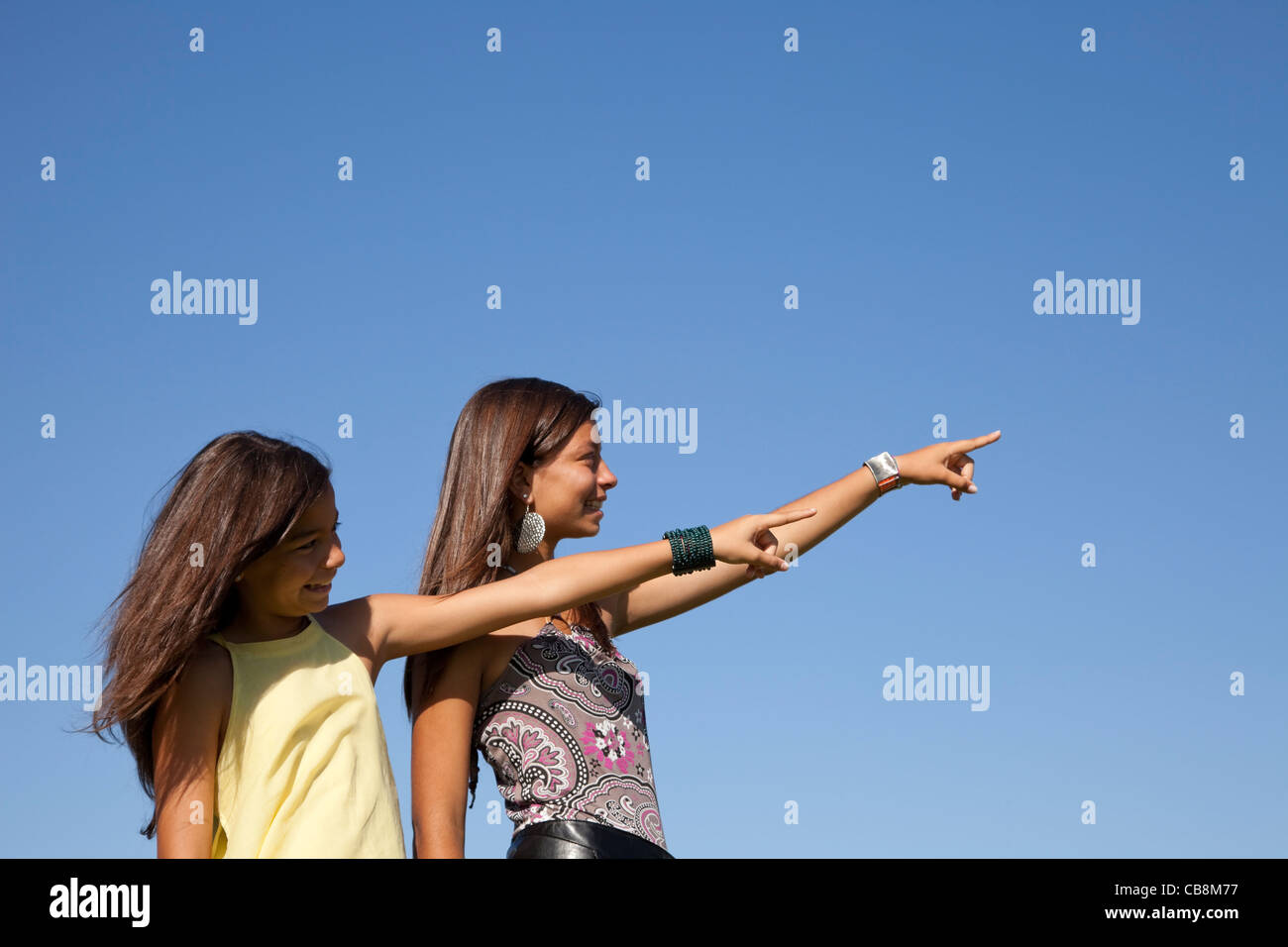 young happy sisters in outdoor pointing away Stock Photo - Alamy