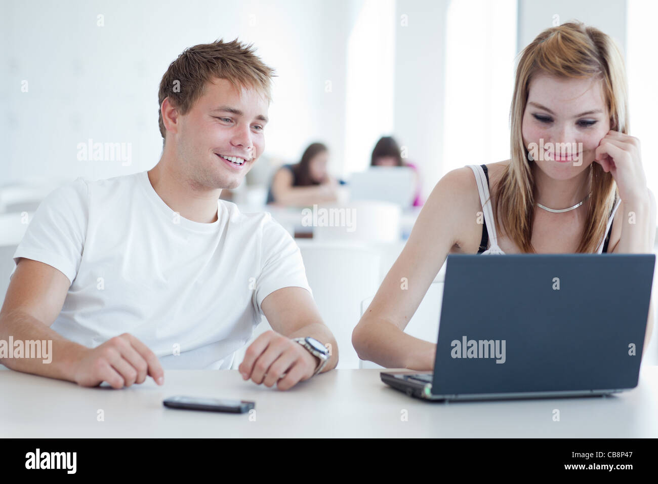 two college students having fun studying together, using a laptop ...