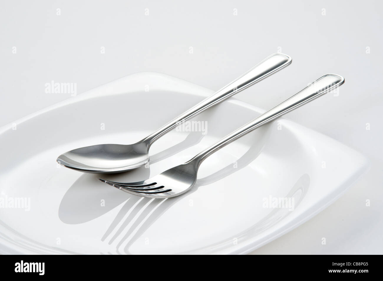Fork and Spoon on white dish Stock Photo - Alamy