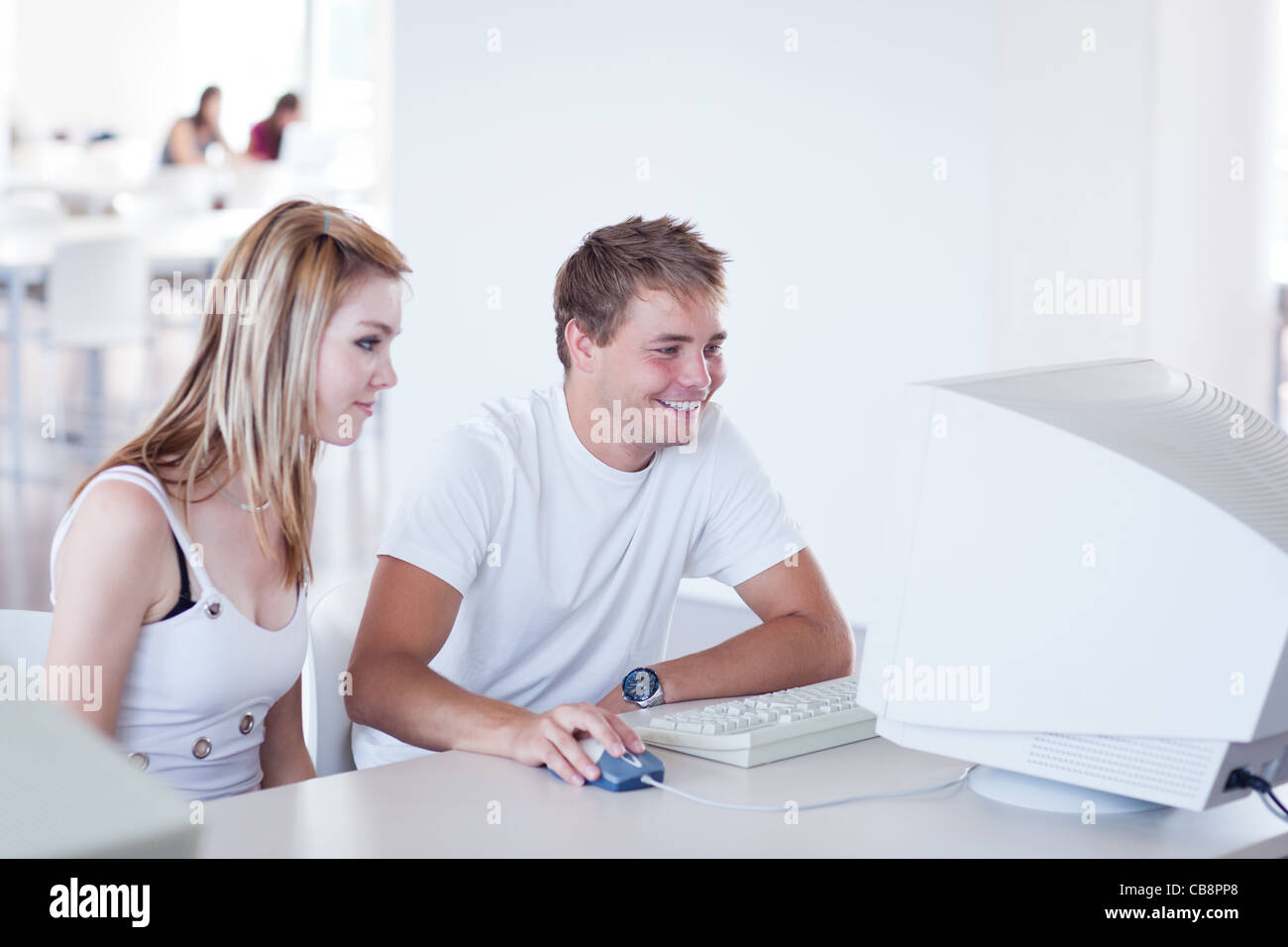 two college students having fun studying together, using a laptop ...