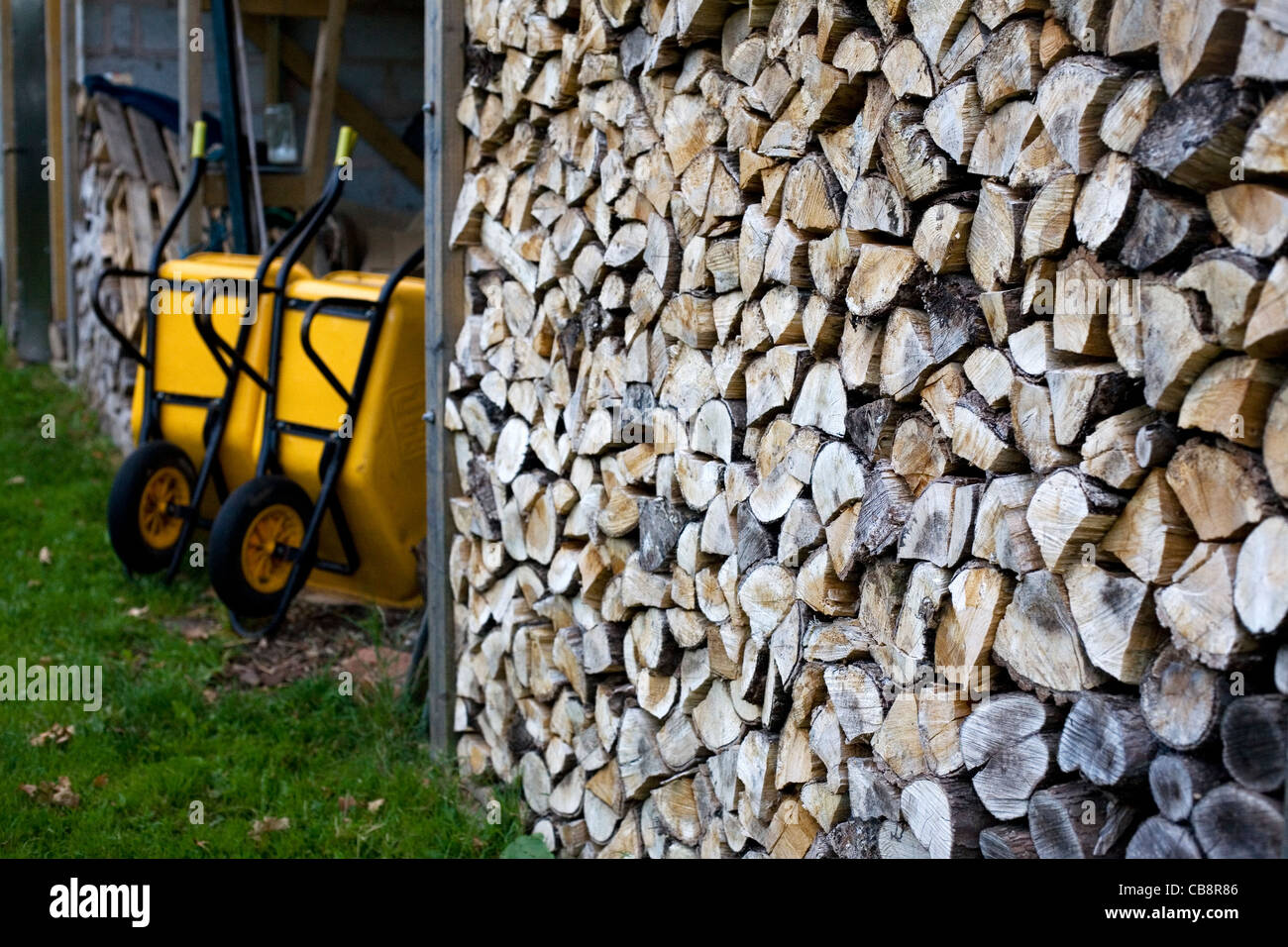 Wheelbarrows and Large Stack of Logs Stock Photo - Alamy