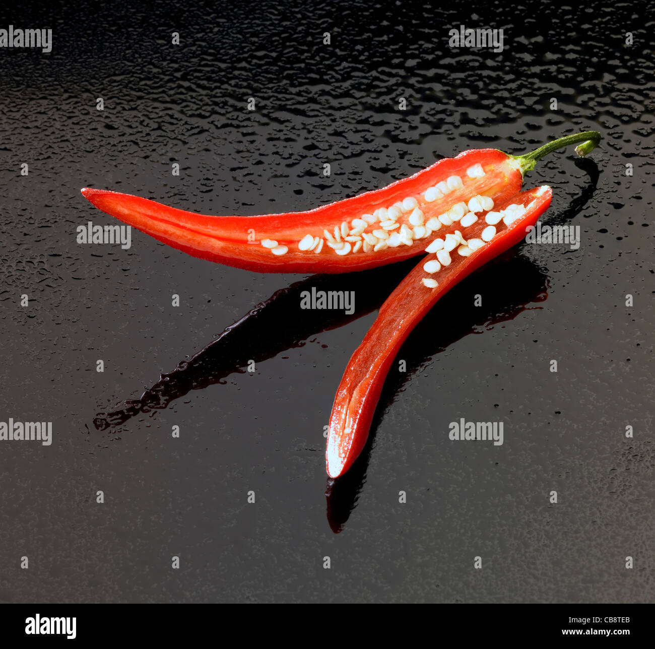 studio shot of a sliced red chili in wet dark reflective back Stock ...