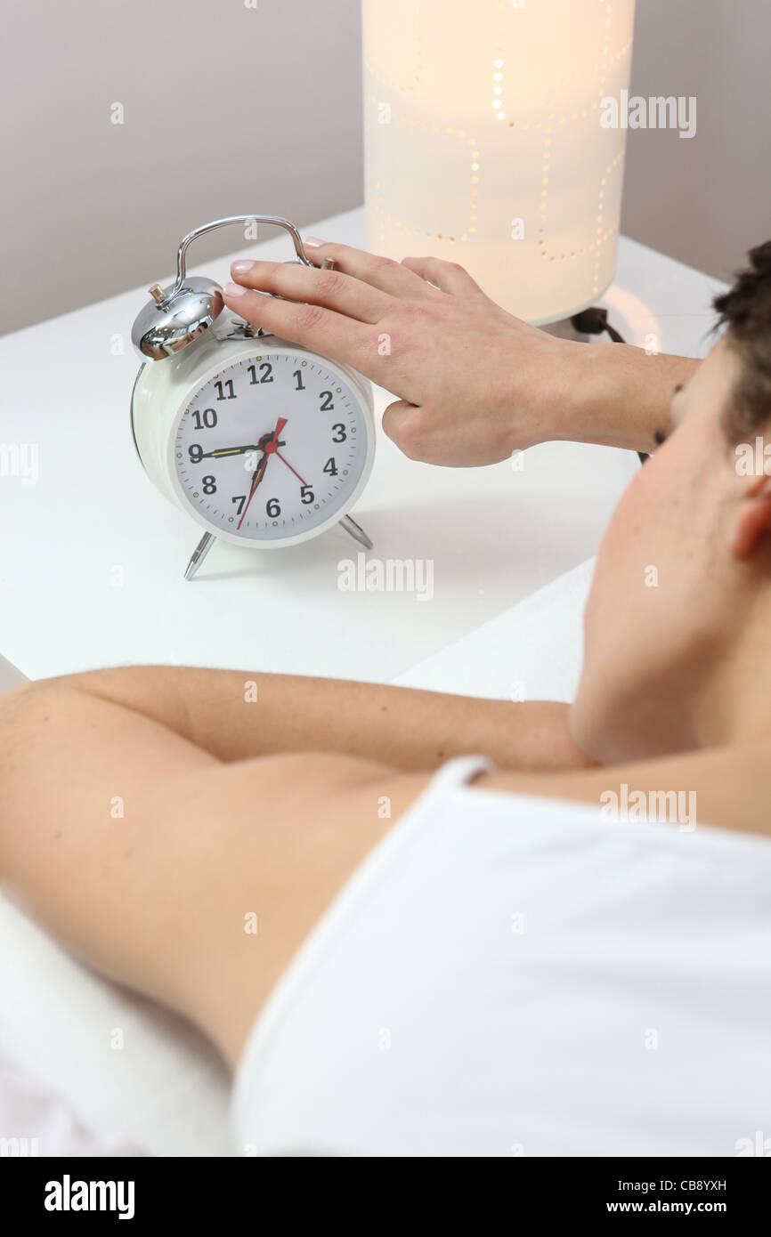 Woman tapping an alarm clock Stock Photo - Alamy