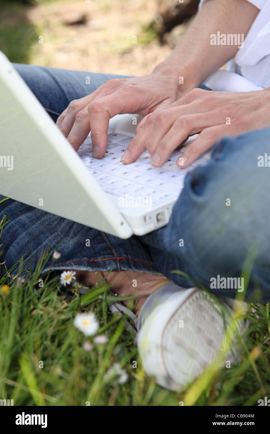 Close-up of woman sat cross legged typing on laptop computer Stock ...