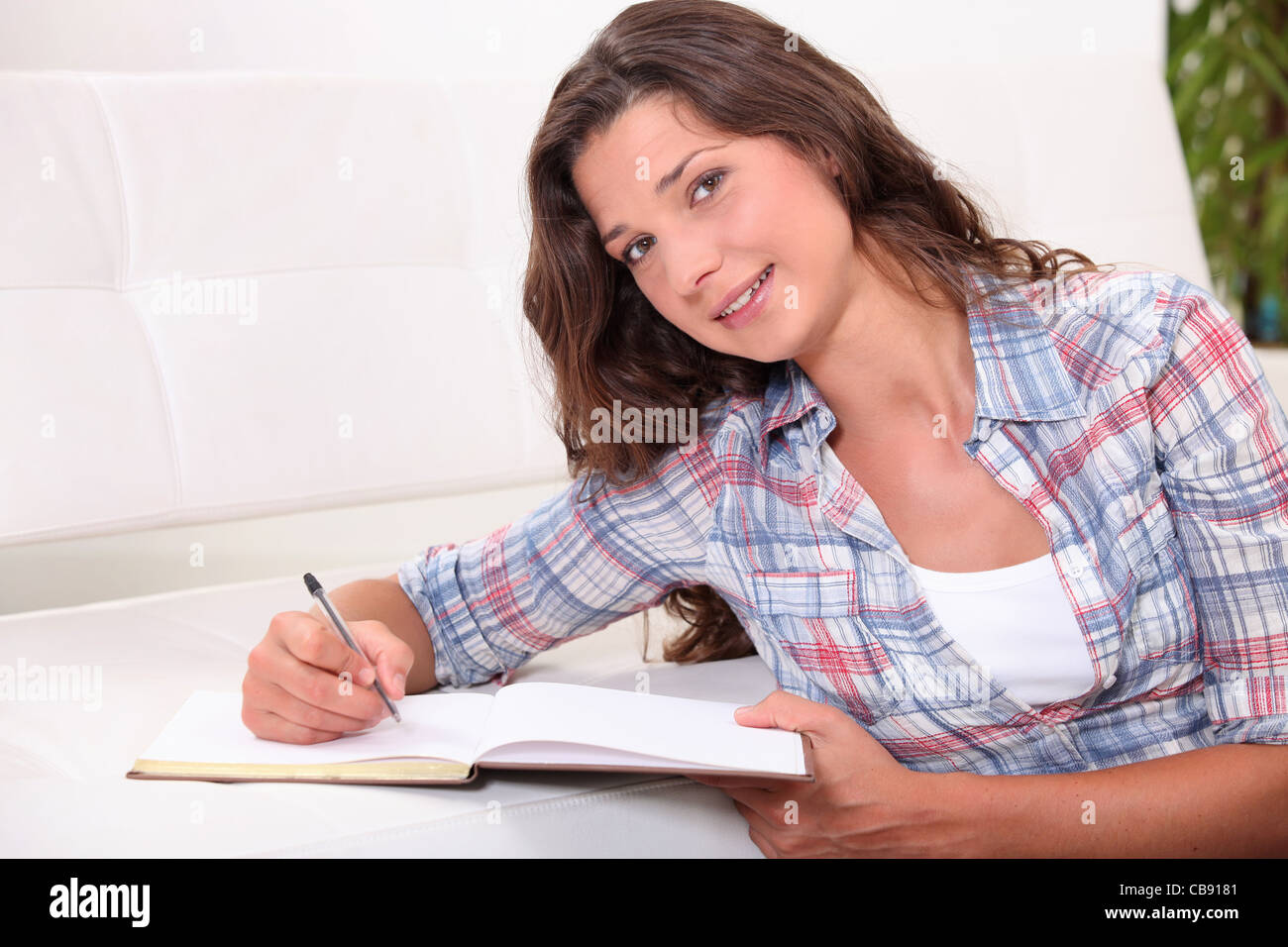 young woman writing on a notebook on a white bench Stock Photo - Alamy