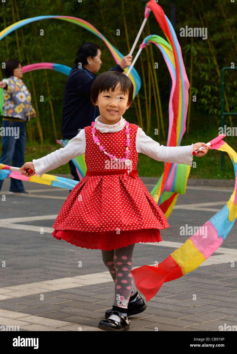 Happy young Chinese girl waving streamers at Zizhuyuan Purple Bamboo ...