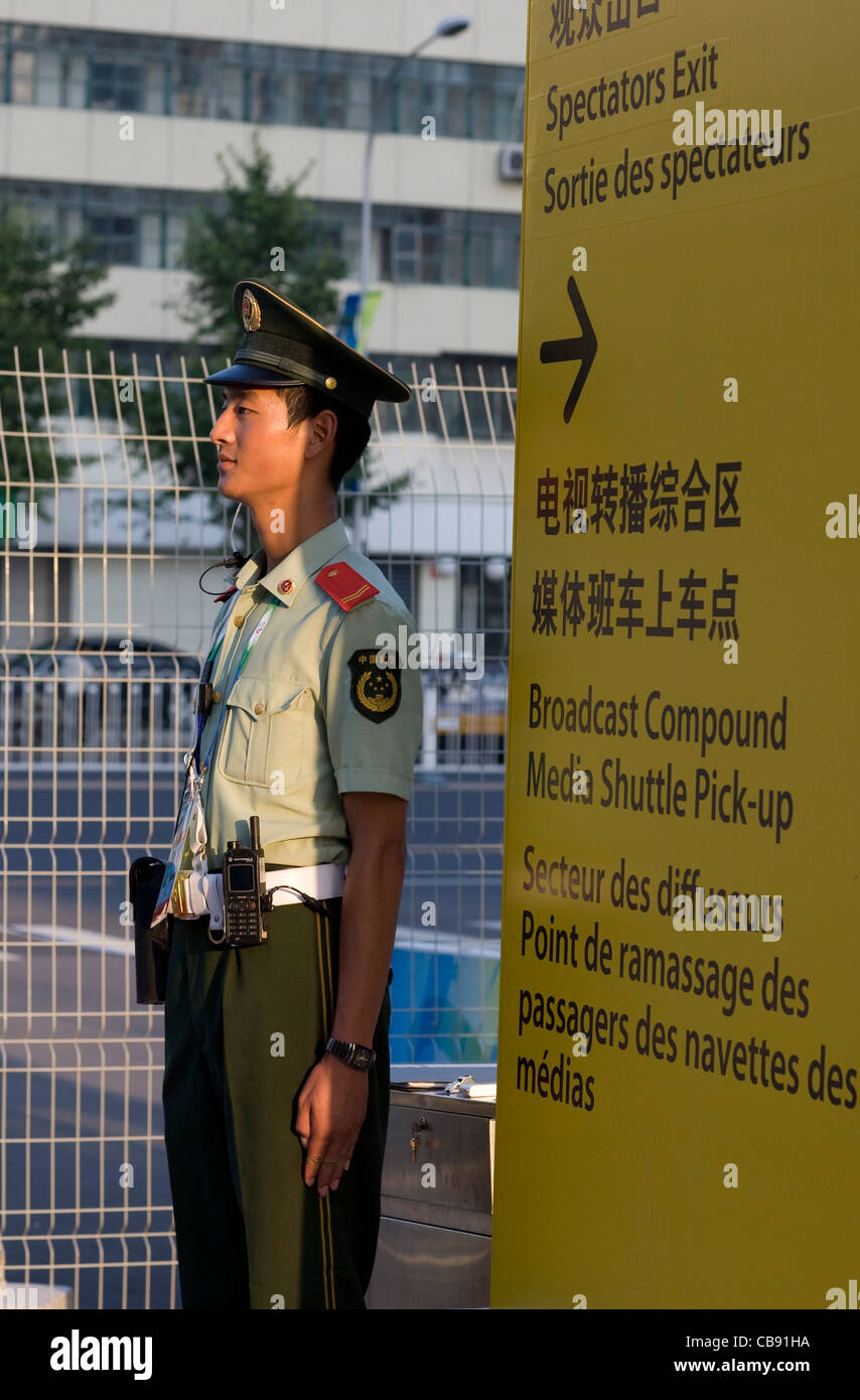 Security guard in uniform stands next to sign written in Chinese ...