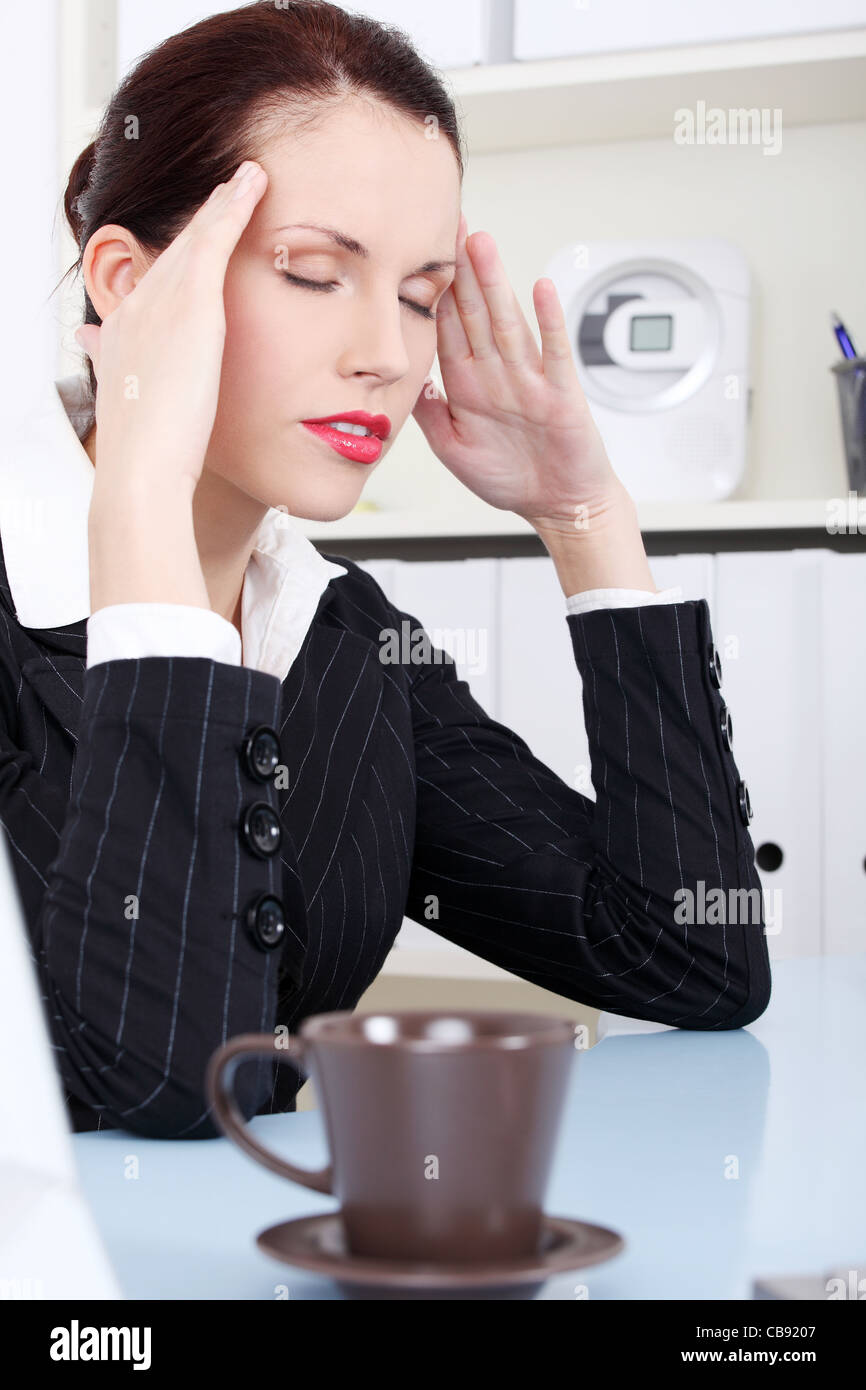 Beautiful caucasian businesswoman having headache and sitting behind ...