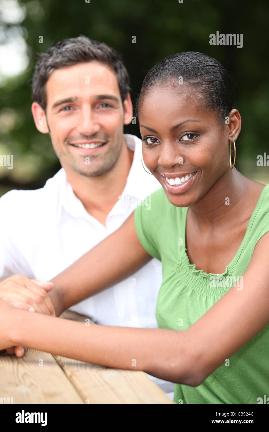 Mixed race couple sat at park table Stock Photo - Alamy