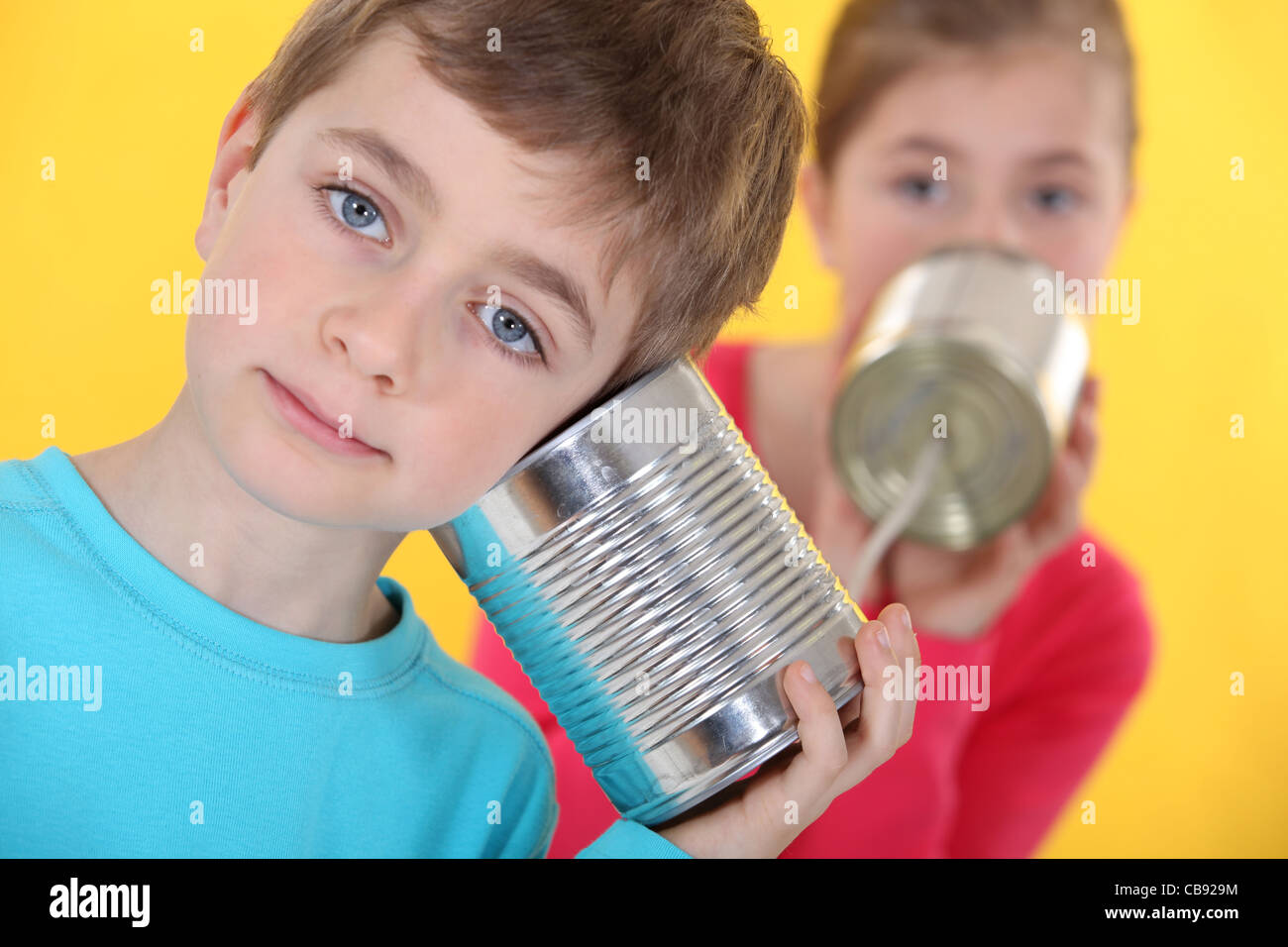 Two kids talking through linked cans Stock Photo - Alamy
