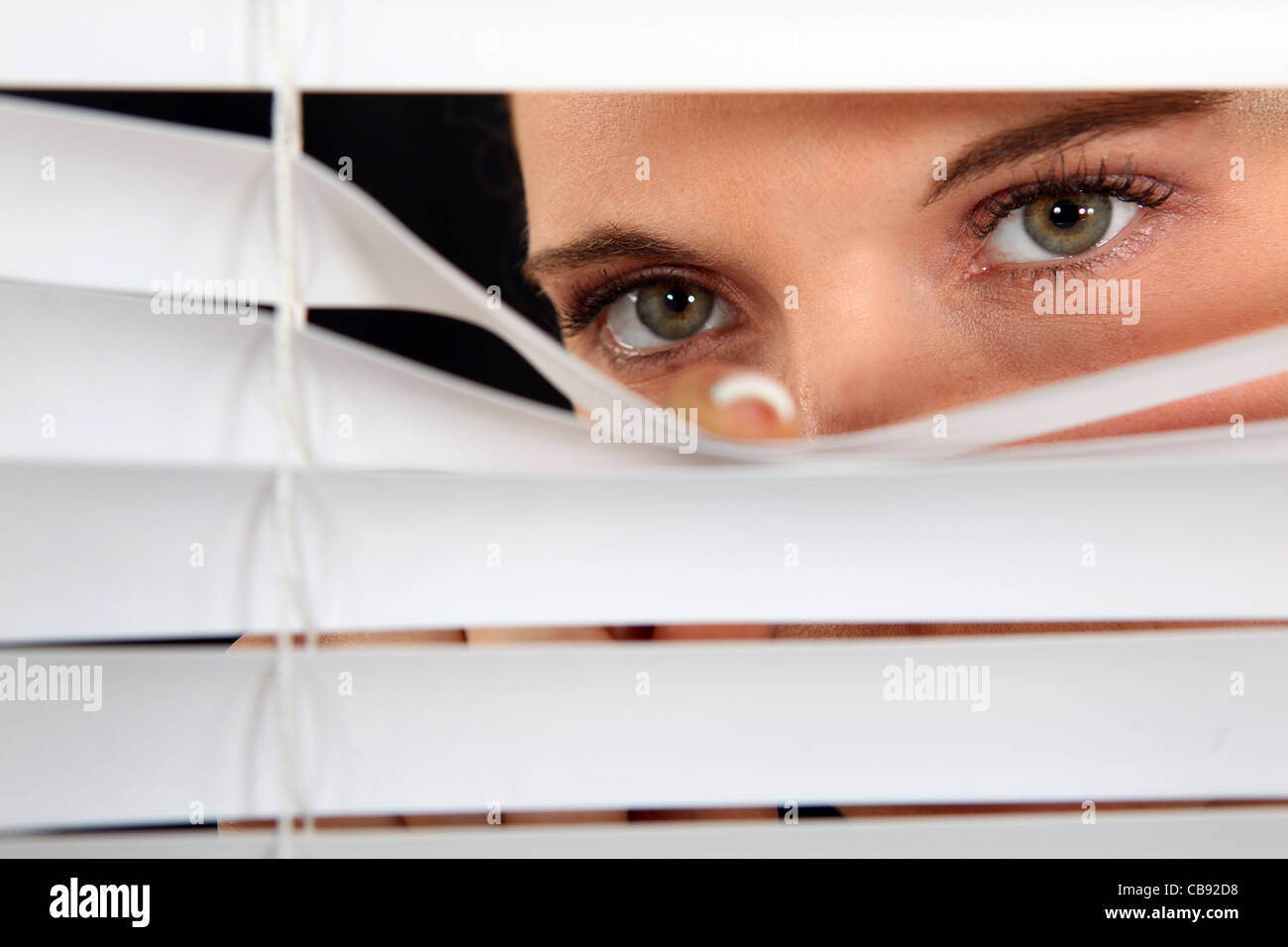 Woman peering through some blinds Stock Photo - Alamy