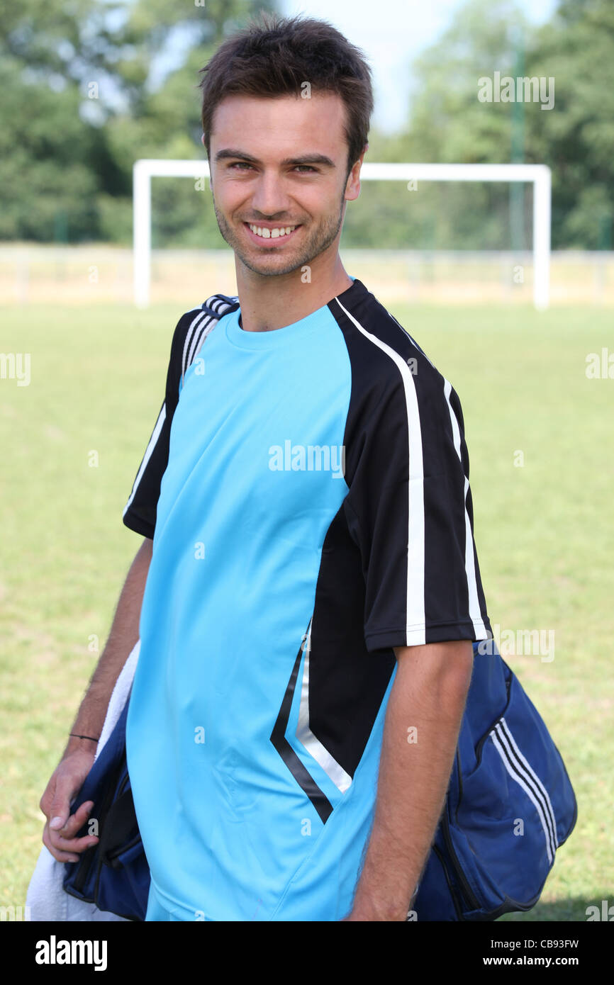 Smiling footballer with kitbag Stock Photo - Alamy