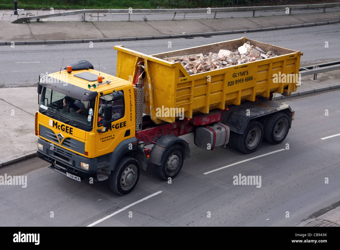 A roll on roll off haulage truck carrying a load of rubble along a road ...