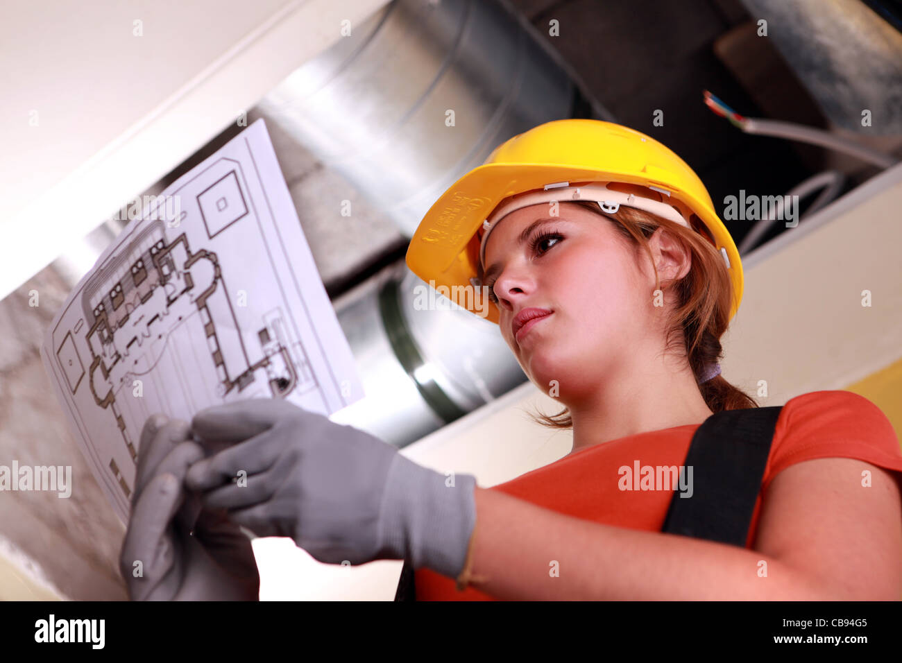 Young female laborer reading plan Stock Photo - Alamy