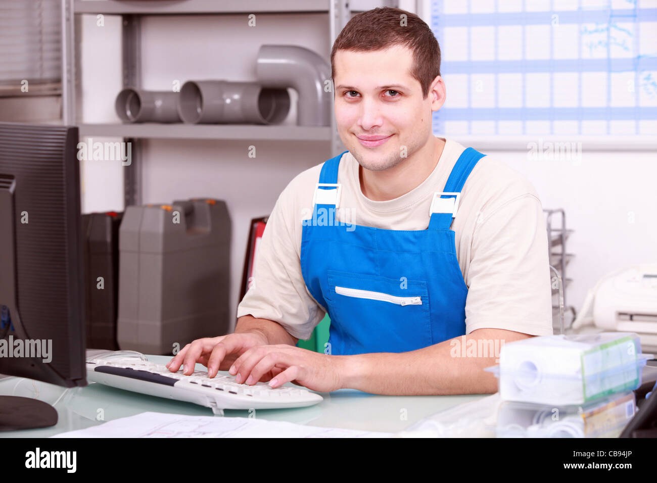 Young plumber in an office working on a computer Stock Photo - Alamy