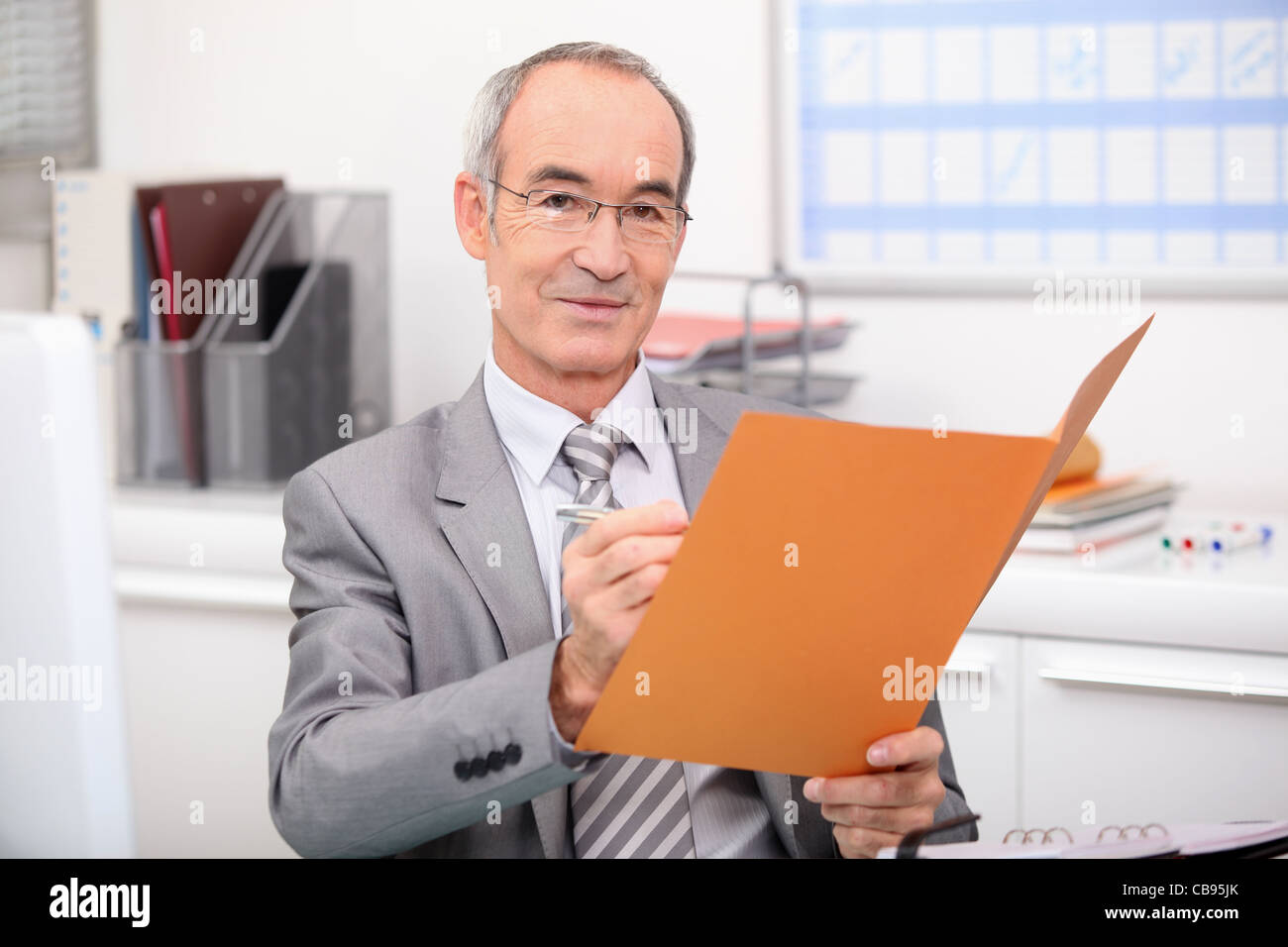 Senior businessman reading a folder Stock Photo - Alamy