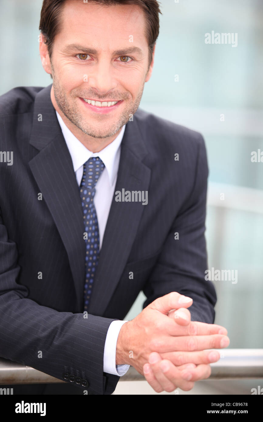 Businessman leaning against railing Stock Photo - Alamy