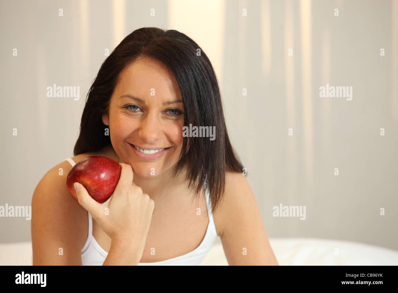 Woman with a red apple in bed Stock Photo - Alamy