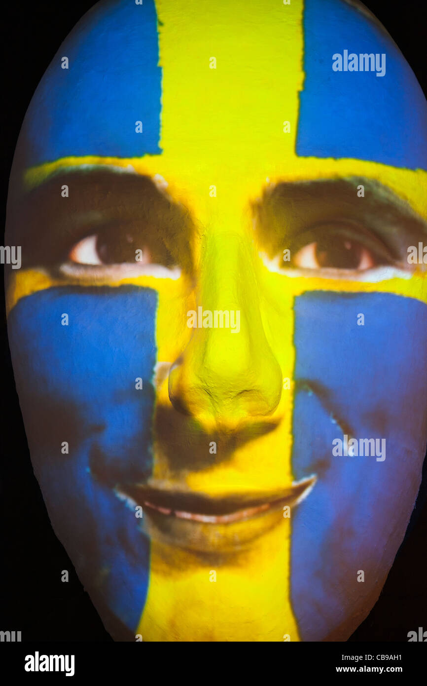 Huge sculpture of a face illuminated by an image of a Swedish flag ...