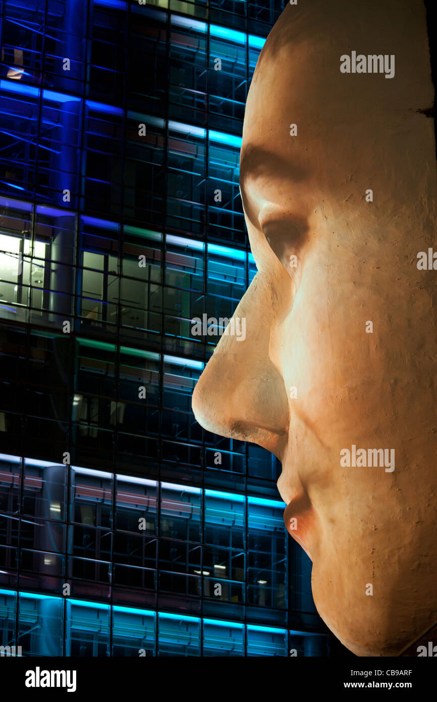 Huge sculpture of a face illuminated by an image of a face during the ...