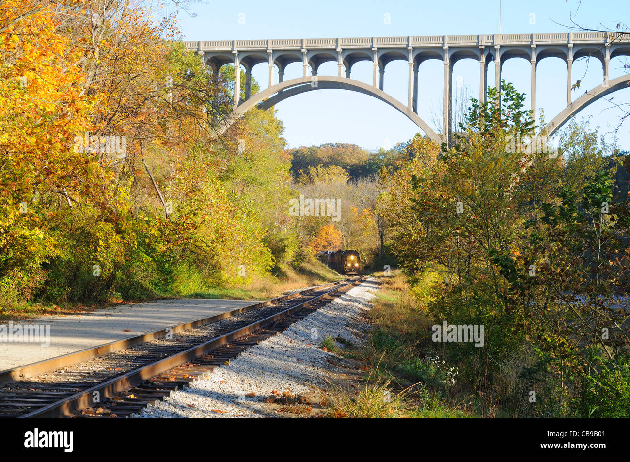 A passenger train rounds a curve and approaches under a high arch ...