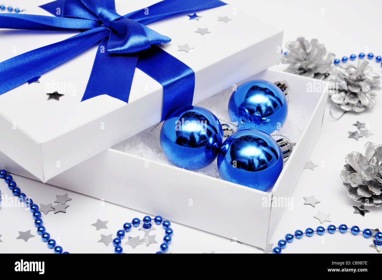 Open gift box with artificial snow and blue Christmas decorations in it ...