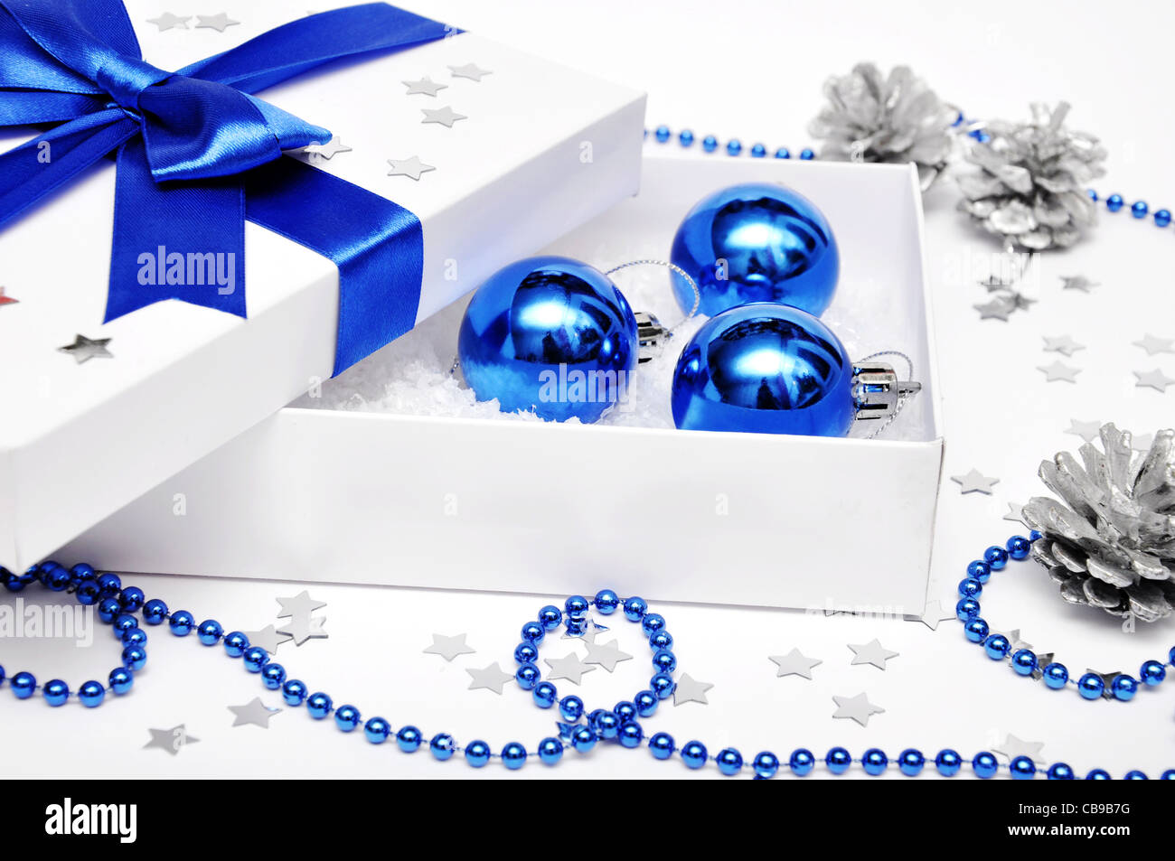 Open gift box with artificial snow and blue christmas decorations in it ...