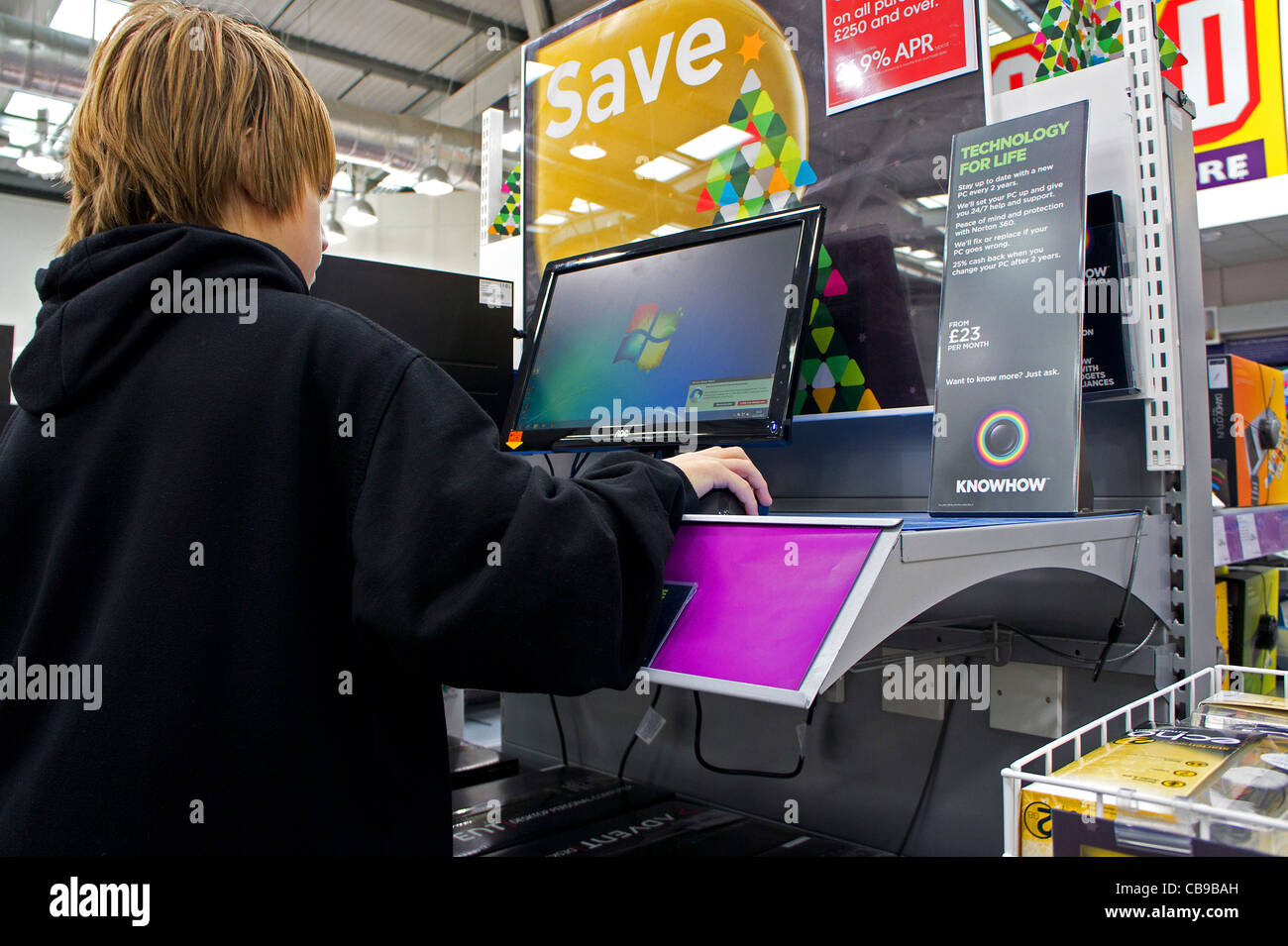 A teenage boy playing on a computer in a PC World store, UK Stock Photo ...