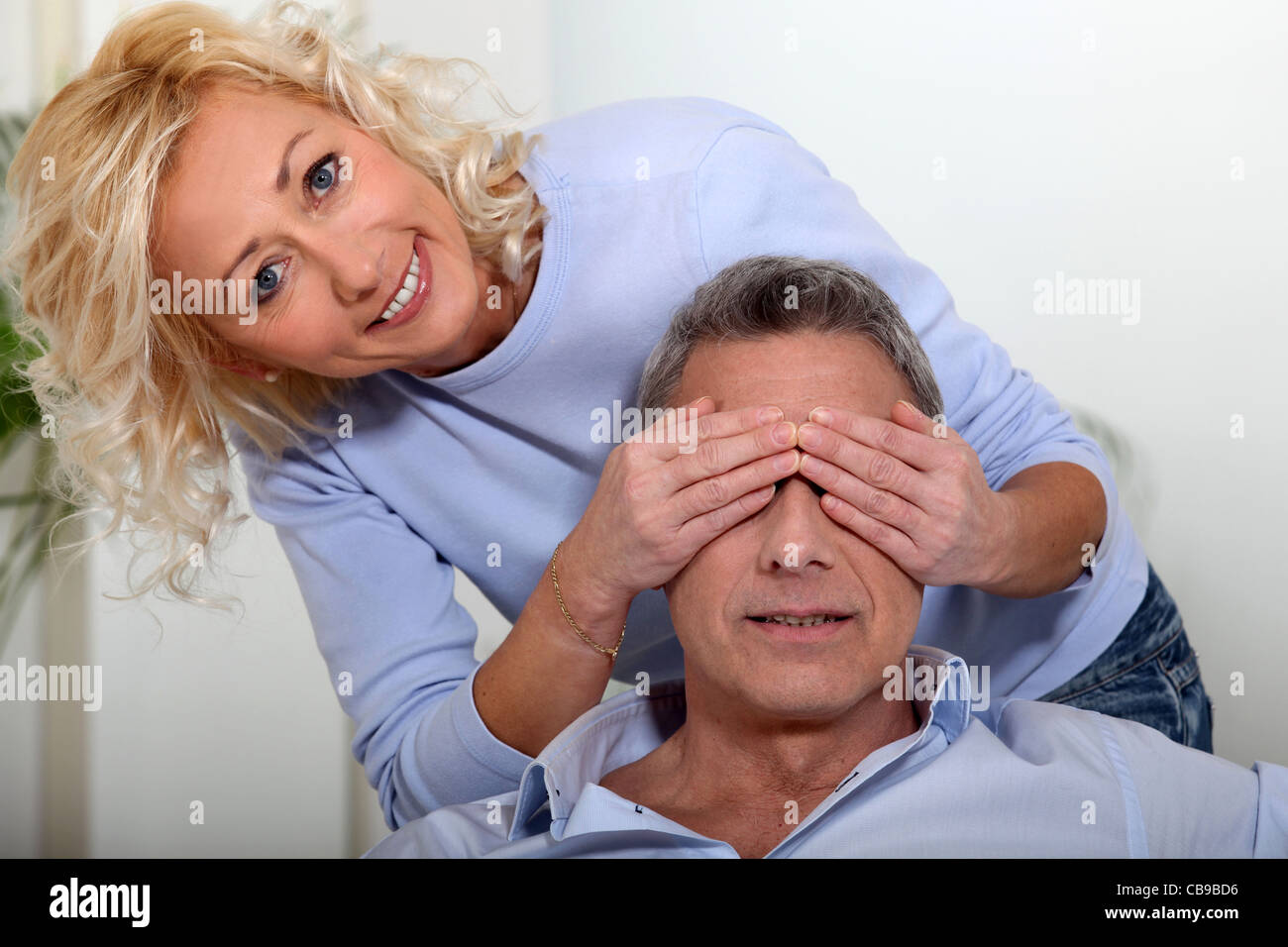 wife covering the eyes of her husband Stock Photo - Alamy