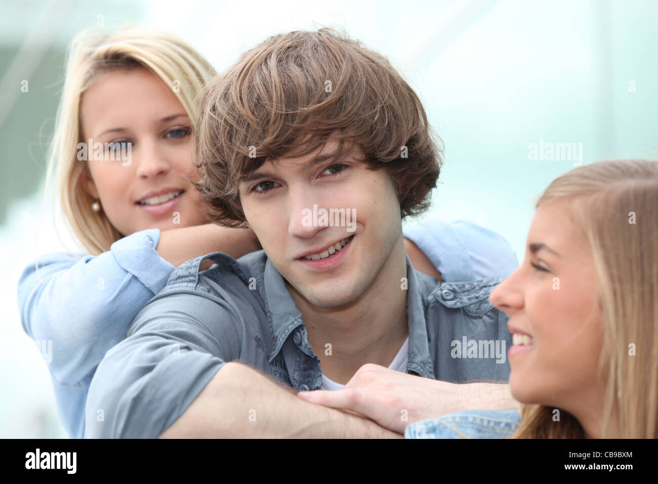 Three smiling teenagers sitting together Stock Photo - Alamy