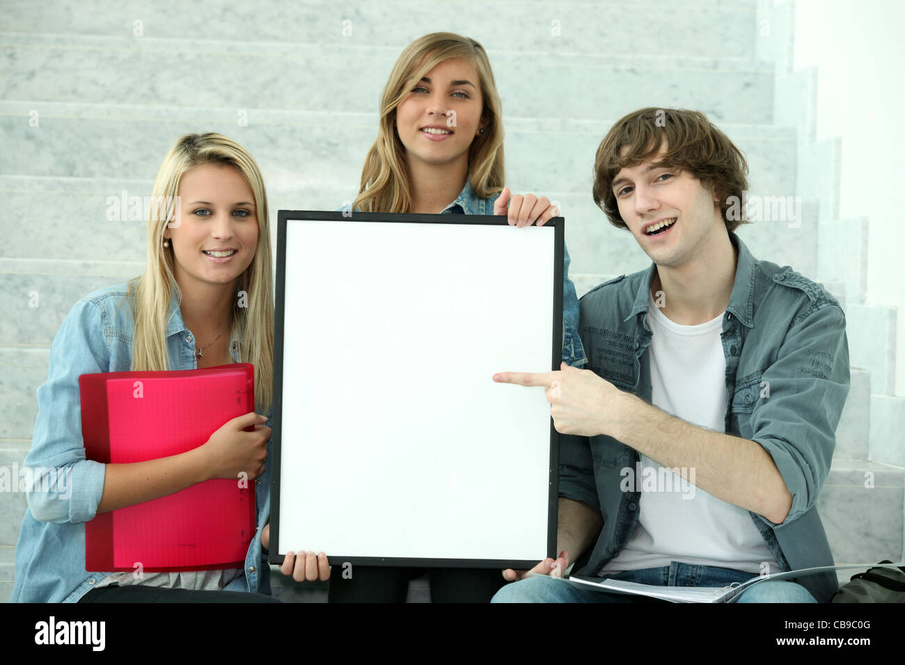 Three students holding a board left blank for your image Stock Photo ...